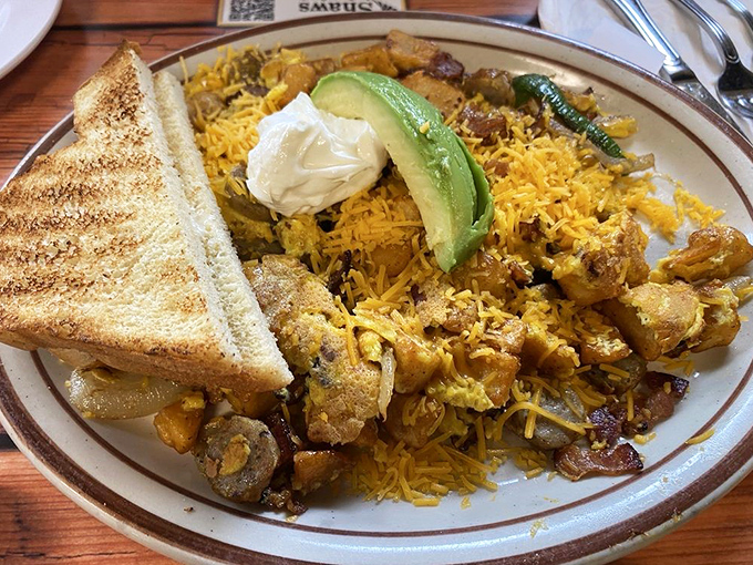 A mountain range of seasoned potatoes with melted cheese, avocado, and eggs – proof that breakfast is the most architecturally impressive meal of the day.