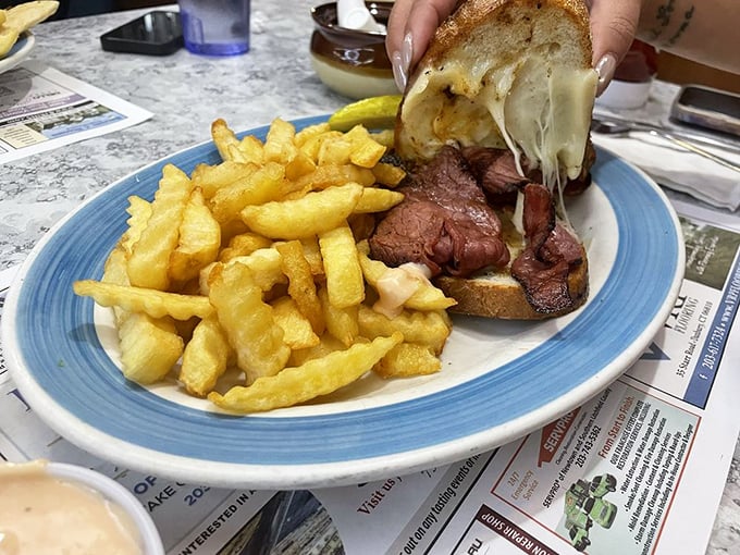 This isn't just a sandwich—it's a Reuben masterpiece with melted cheese cascading over tender meat, demanding to be photographed before it's devoured.