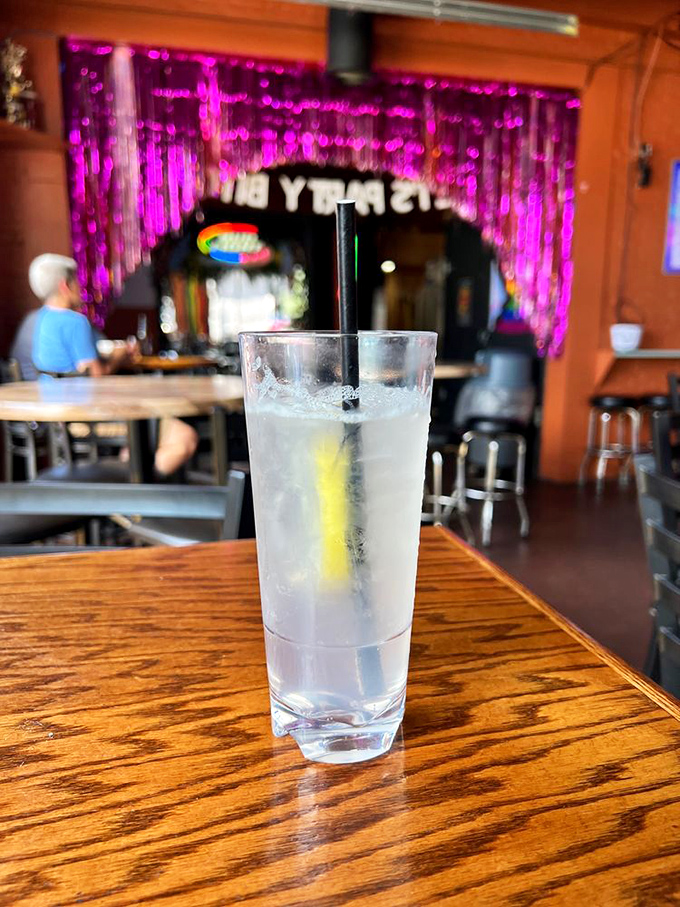 A tall glass of refreshment sits before vibrant décor. Sometimes the simplest drinks are the perfect palette cleansers between pizza slices.