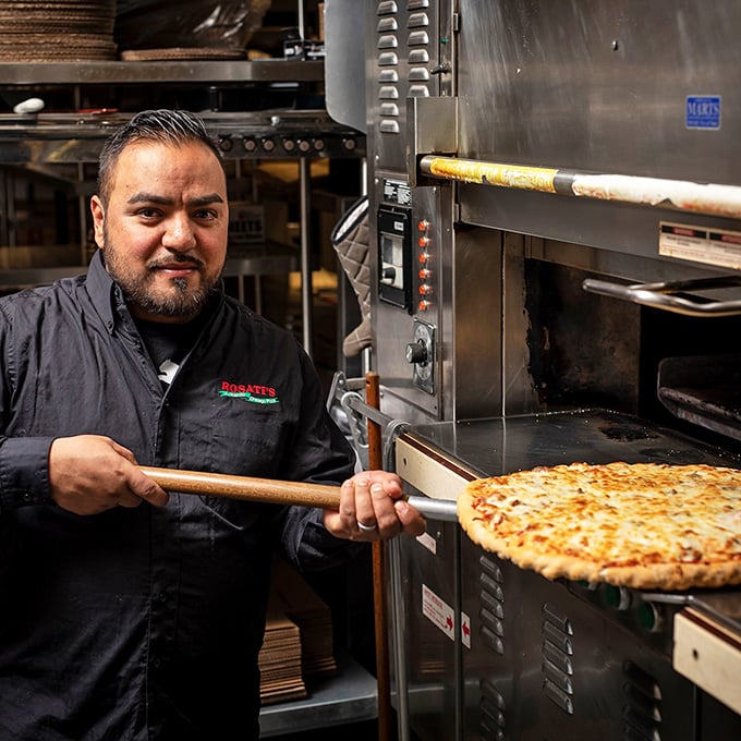 Pizza artisans at work—where wooden paddles are extensions of hands and ovens are portals to deliciousness.