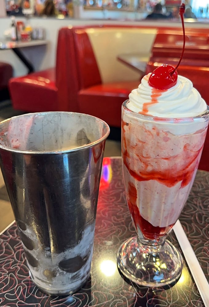 A strawberry shake that belongs in a museum of American classics—tall, proud, and topped with a cherry that's more than just decoration.
