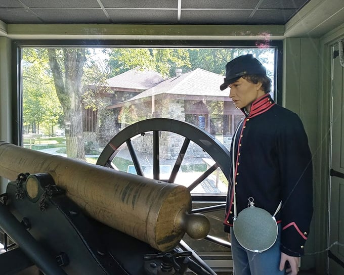 A mannequin in Civil War uniform stands sentinel beside the historic cannon, frozen in time like he's waiting for someone to invent smartphones so he can check his email.