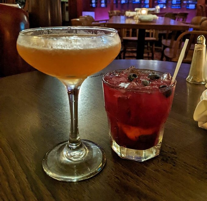 Cocktails that look like liquid jewelry—one amber, one ruby—both promising an evening where worries dissolve faster than the ice.