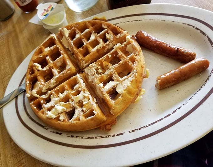 Golden waffle perfection with sausage links standing at attention—a breakfast plate that says "Good morning" with more enthusiasm than you can muster before coffee.