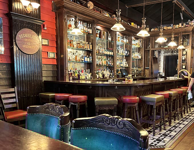 The bar gleams with bottles of amber promise, while red walls and leather stools invite you to settle in for "just one more."