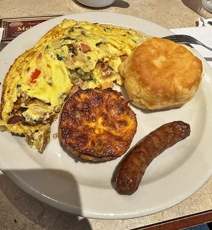 Breakfast done right: a fluffy omelet, golden biscuit, and sausage link that make waking up early almost worth it—almost.