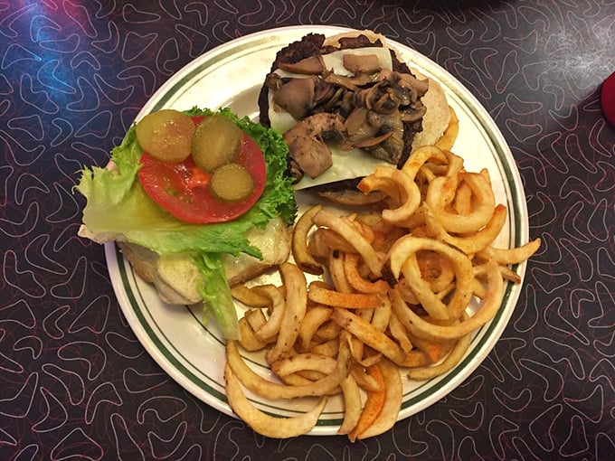 A classic diner burger with a mountain of curly fries – proof that sometimes the simplest pleasures are the ones that keep us coming back for more.
