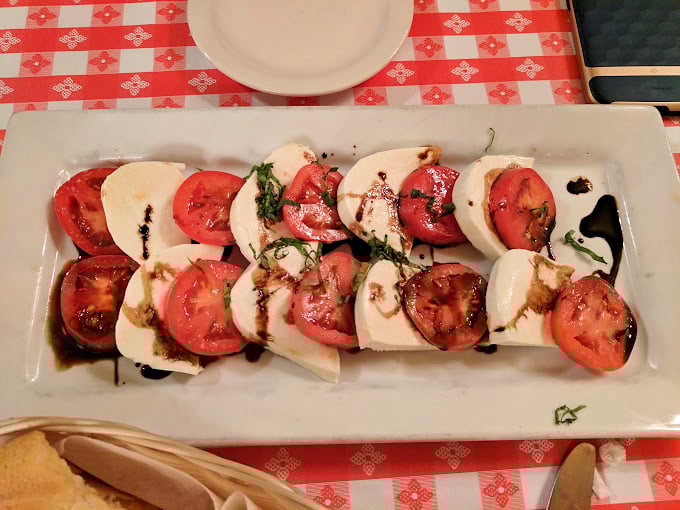 Caprese salad arranged like edible dominoes – when tomatoes and mozzarella play nice, everybody wins the game.
