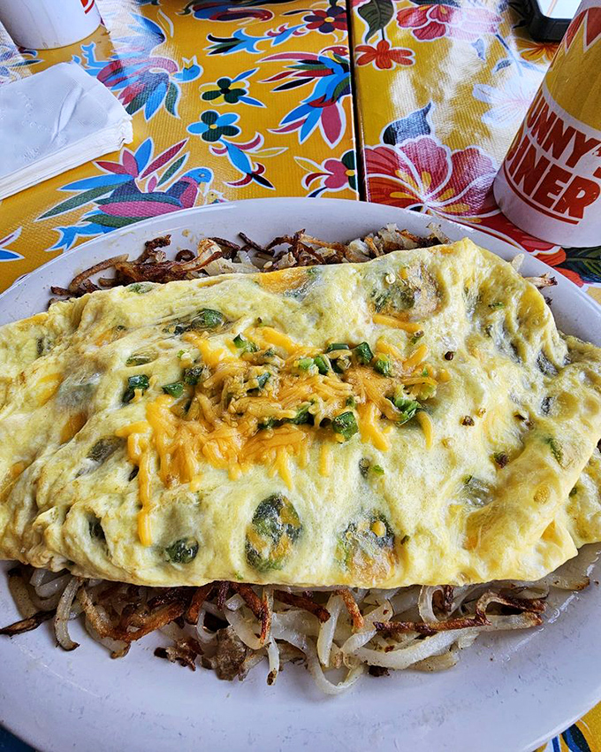 An omelet that understands cheese isn't just an ingredient but a philosophy – folded around perfectly sautéed vegetables with hash brown bedding.