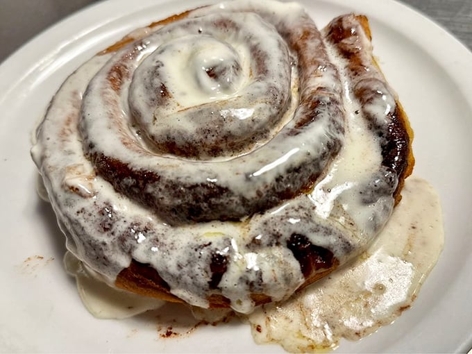 This cinnamon roll isn't just breakfast—it's dessert masquerading as morning food, swimming in a pool of glorious icing.