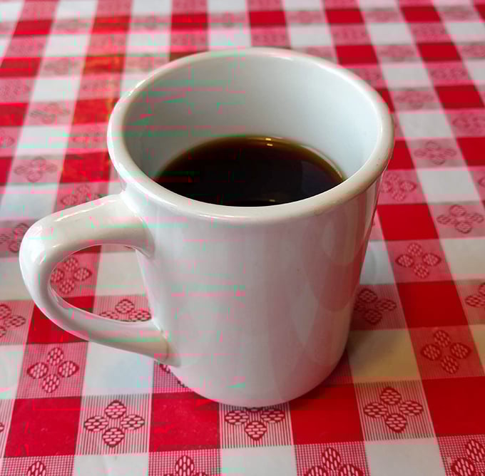 A simple white mug of diner coffee on a checkered tablecloth—proof that life's greatest pleasures don't need fancy packaging.