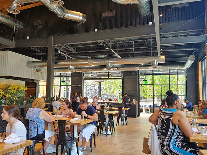 Diners enjoying the bright, airy space where exposed ductwork meets natural light. Here, eating well becomes a social event rather than a solitary penance.