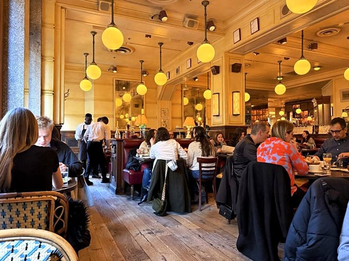 The warm glow of pendant lights transforms ordinary diners into characters in a delicious French film. Everyone looks better in this lighting—even the food.