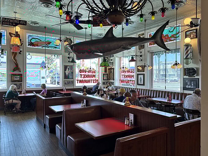 Where wooden booths become front-row seats to the seafood show. Note the shark suspended from the ceiling—purely decorative, not menu-related.
