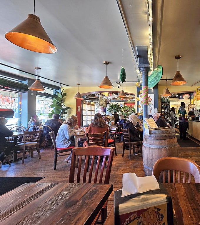 Pendant lights cast a warm glow over diners deep in conversation and deeper in sandwich bliss—the universal language of good food.