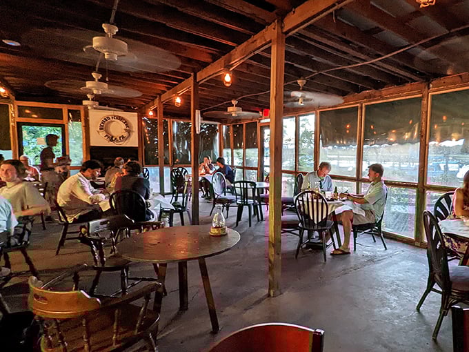 The screened porch dining area – where the coastal breeze mingles with the aroma of fresh seafood and conversations flow as easily as the nearby tides.