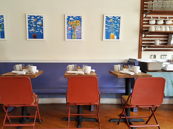 Bright artwork against blue wainscoting creates the perfect backdrop for these coral chairs – like a Wes Anderson film set where the food actually tastes good.