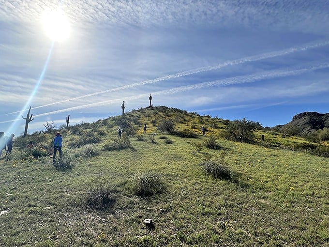 Hikers ascending toward that perfect Instagram moment, where desert meets sky and everyday worries shrink to the size of a cholla cactus below.