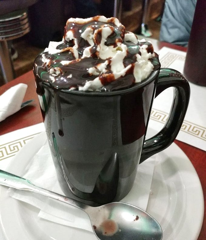 Hot chocolate that doesn't mess around—topped with a cloud of whipped cream and chocolate drizzle that makes Swiss Miss weep with inadequacy.