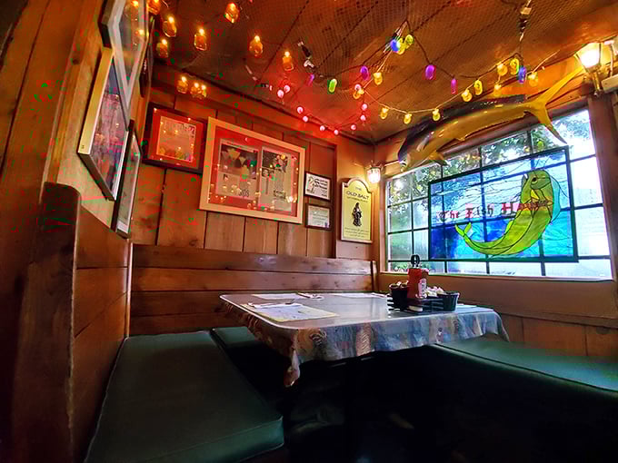 Cozy booth seating beneath a stained glass mermaid window—this corner spot feels like being inside a ship captain's favorite hideaway.