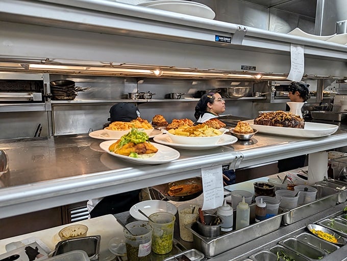 Behind the scenes, the kitchen ballet unfolds—plates lined up with military precision waiting for their grand entrance to your table.