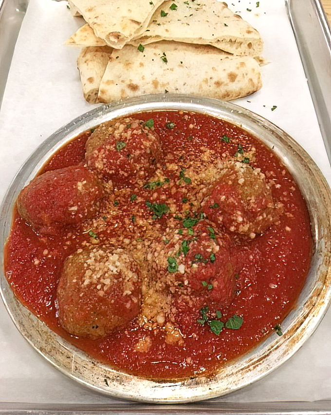 These meatballs don't just sit in sauce—they luxuriate in it, waiting for you to tear off a piece of bread and create the perfect bite.