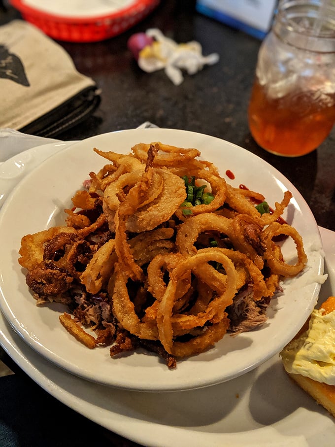 These crispy onion rings aren't just a side dish – they're golden halos crowning a kingdom of pulled pork below.