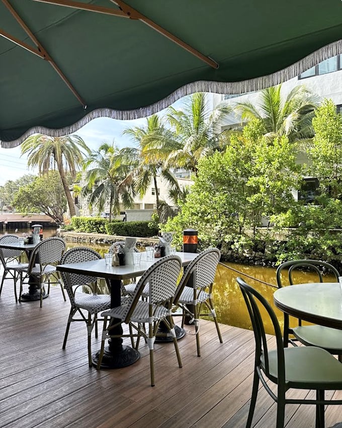 Dining under those fringed green umbrellas with palm trees swaying nearby—it's the Franco-Florida mash-up you never knew you needed.