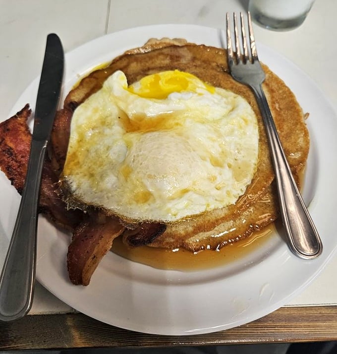 A pancake topped with a perfectly fried egg and bacon—breakfast doesn't need to be complicated to be extraordinary. This is morning joy on a plate.