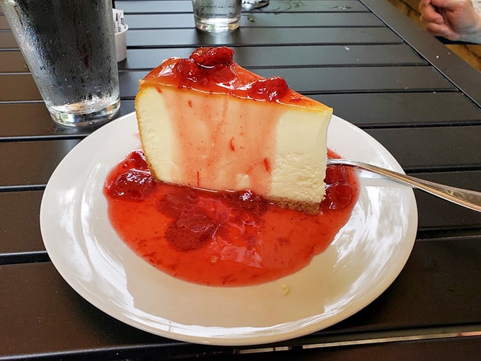 Panna cotta swimming in strawberry sauce—the kind of dessert that makes you seriously consider licking the plate when nobody's looking.