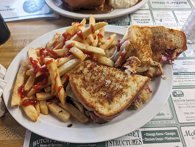 The Reuben sandwich – where corned beef, sauerkraut and melted cheese create a symphony of flavors. Those ketchup-drizzled fries are the perfect sidekick.