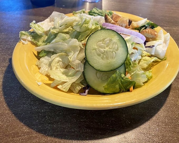 Even the side salad gets respect here—crisp, fresh, and vibrant on a sunny yellow plate that brightens the whole table.