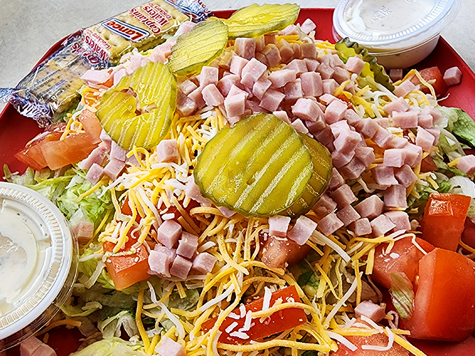 This isn't just a salad—it's a celebration of abundance. Pickles standing guard over a mountain of ham, cheese, and fresh vegetables.