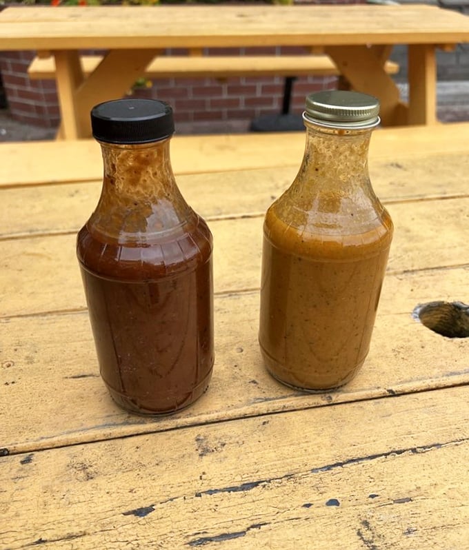 Two bottles of house-made sauce sitting pretty on a wooden table—one sweet, one tangy, both essential to the experience.