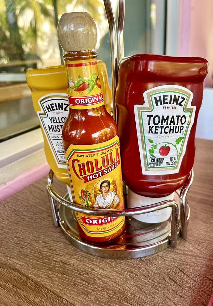 The condiment caddy—where Cholula, ketchup, and mustard form the holy trinity of flavor enhancement for whatever massive plate arrives next.