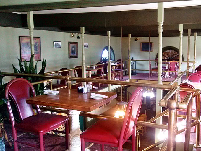 Ruby-red chairs pop against warm wood tones in this dining car seating area. The brass railings aren't just decorative—they're portals to railroad dining's heyday.
