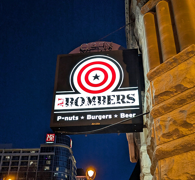 As night falls, the AJ Bombers sign glows like a beacon for the burger-obsessed. "P-nuts • Burgers • Beer" is less a tagline than a promise.