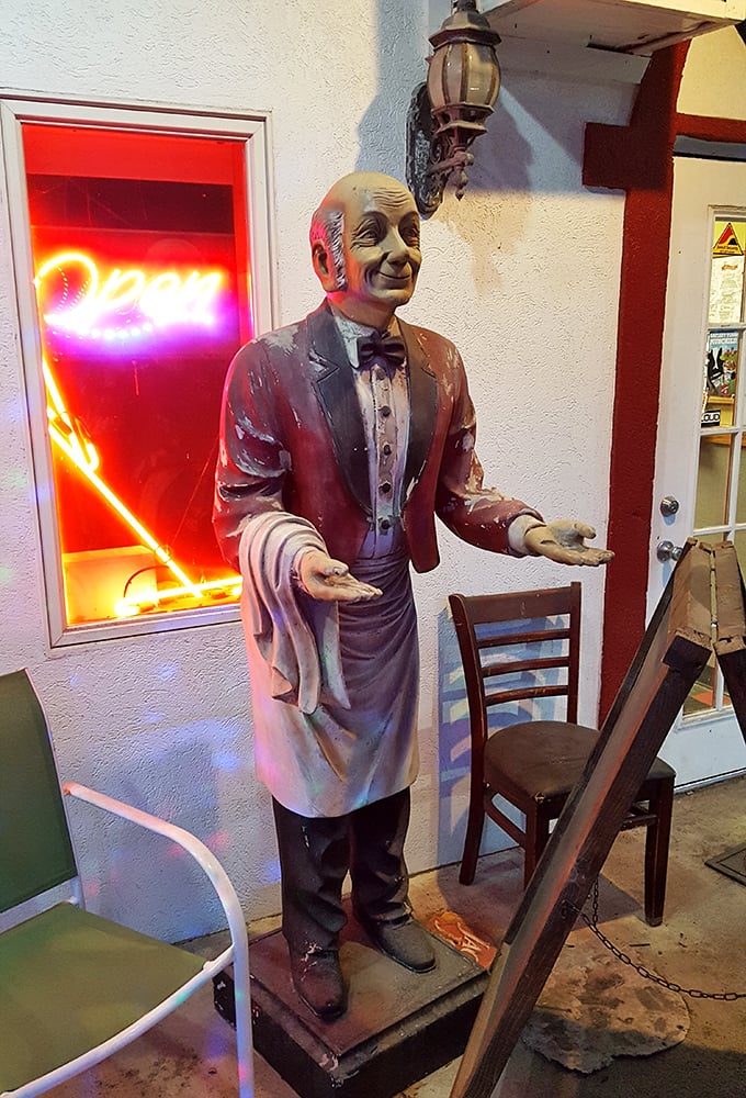 The silent maître d' who never judges your order. This vintage waiter statue has seen thousands of pizza lovers come and go through these doors.