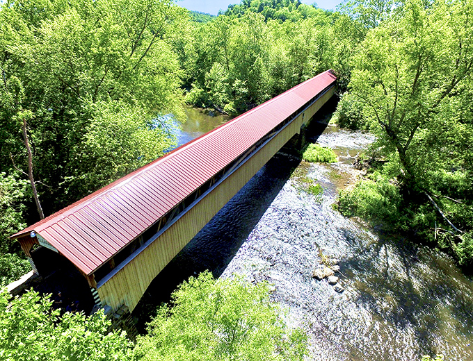 From above, the bridge's impressive length becomes apparent, stretching like a russet ribbon across the sparkling creek.