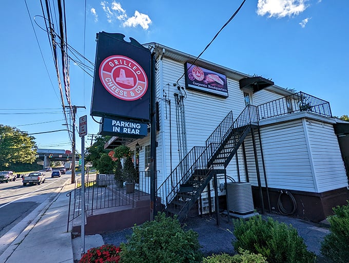 Grilled Cheese & Co.'s charming white building houses comfort food wizardry. That circular sign promises cheesy perfection ahead.