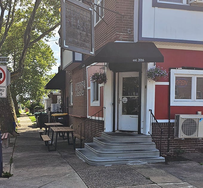 Northeast Sandwich Co.'s wooden sign swings above a classic brick building. A Philadelphia corner spot where sandwich innovation meets neighborhood charm.