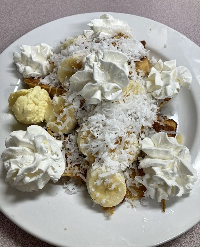 Coconut and banana French toast that makes you question why regular toast even exists—whipped cream islands dot this sweet morning archipelago.