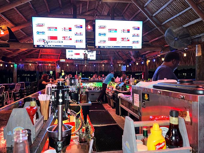 The thatched tiki bar—where tropical drinks flow and worries evaporate faster than Florida rain on hot pavement. Paradise found.