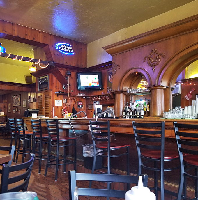 The bar area beckons with its warm wood tones and classic design—a place where strangers become friends over cold drinks and hot plates.