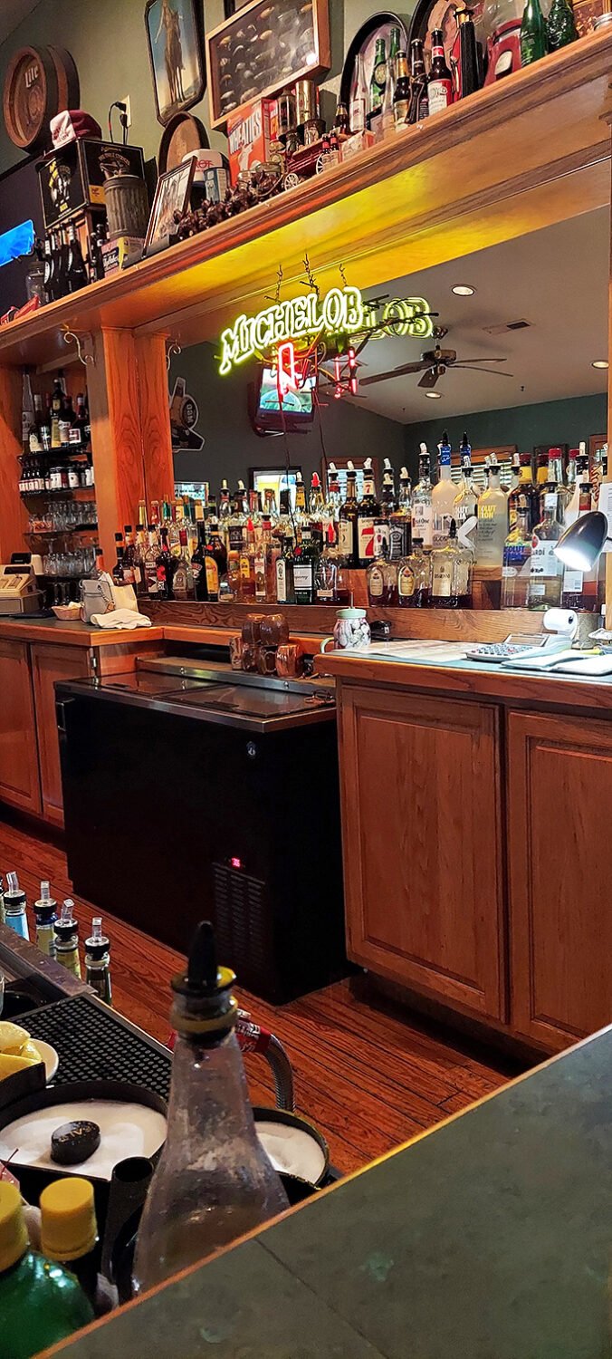 The bar's neon glow promises libations worthy of pairing with your steak. Those bottles aren't just decoration—they're potential memories.