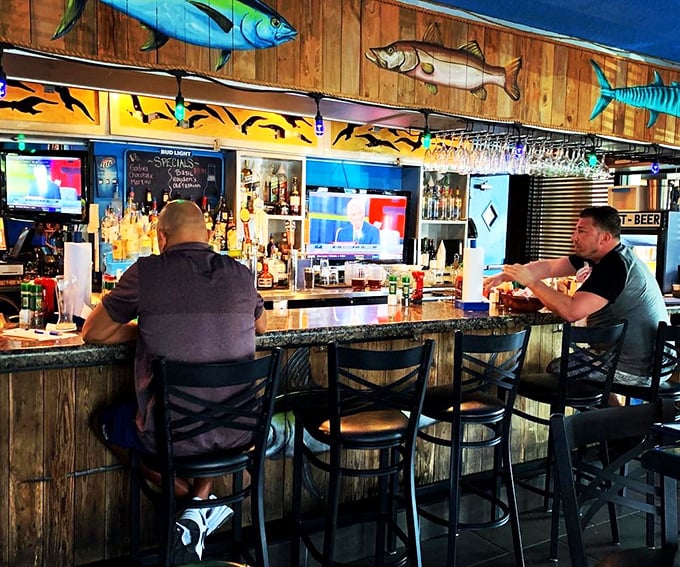 The bar area, where fishing tales get taller with each round. Those wooden fish mounted above aren't just decor – they're silent witnesses to decades of stories.