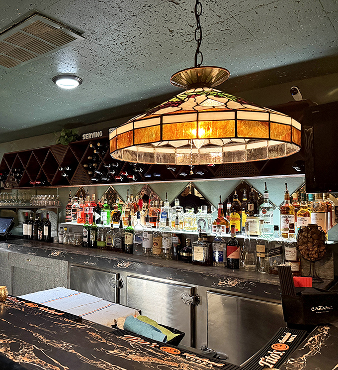The bar's Tiffany-style lamp casts a warm glow over decades of spirits – some bottles might be newer than others, but the hospitality is consistently vintage.