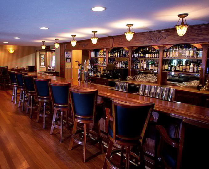 The bar beckons with its warm wood tones and promise of expertly crafted cocktails—resistance is futile.