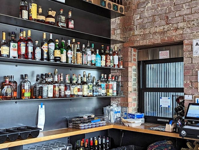 The bar shelves tell a story of thoughtful curation – a liquid library where bourbon and craft spirits stand ready to complement smoky flavors.