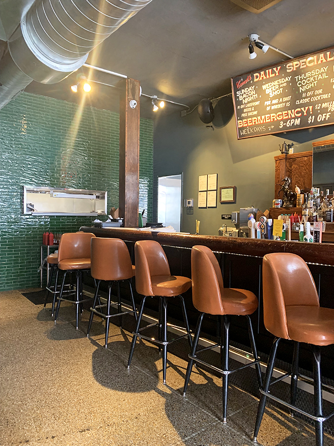 Caramel-colored bar stools line up like patient sentinels. The emerald tile backsplash adds a pop of color to this cozy corner.